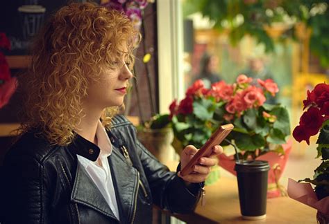 곱슬 금발의 젊은 여자는 종이 컵과 휴대 전화와 꽃 옆에 카페에 앉아 개념에 대한 스톡 사진 및 기타 이미지 개념 곱슬