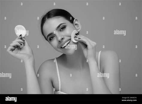 Beautiful Young Woman With Cotton Pad Applying Lotion On Face