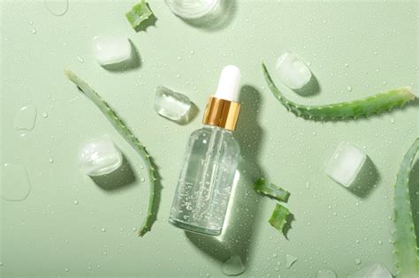 밝은 녹색 배경에 스포이드 얼음 조각 알로에 잎이 있는 투명한 화장품 병 알로에 베라 추출물 노화 방지 피부 관리 보습 및 클렌징의 개념 공간을 복사합니다 알로에베라에 대한