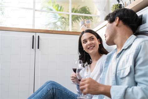 아시아의 젊은 신혼 부부는 집에서 부엌에서 함께 시간을 보낸다 매력적인 낭만적 인 남자와 여자는 가족 관계 생활과 새 집으로 이사하는 것을 축하하기 위해 와인을 마신다