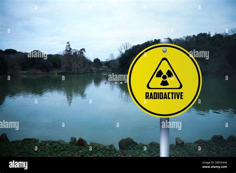 Radioactive Pollution Yellow Warning Sign With Hazard Symbol Near Lake
