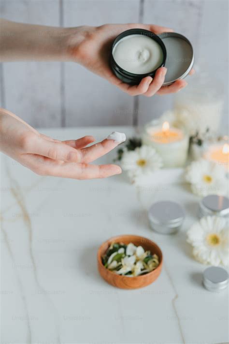 꽃 한 그릇 위에 촛불을 들고 있는 사람 사진 Unsplash의 핸드 크림 이미지