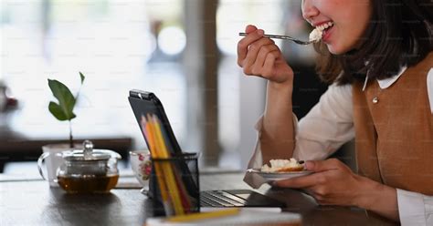 컴퓨터 태블릿으로 일하고 카페에서 디저트를 먹는 여성의 자른 샷 사진 Unsplash의 사업 이미지