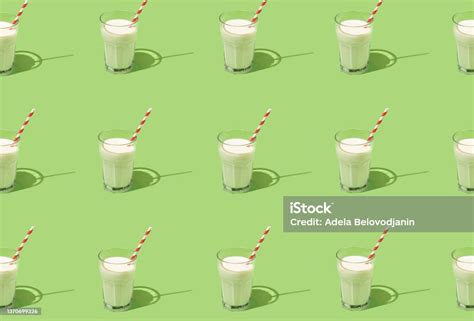 파스텔 녹색 배경에 우유 와 빨간색과 흰색 종이 빨대 의 유리로 만든 창조적 인 패턴 복고풍의 미적 스타일 최소한의 창조적 인