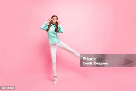거리를 걷는 재미있는 아가씨의 전신 사진은 아름다운 시력 착용 사양 청록색 셔츠 흰색 바지 고립 된 핑크 컬러 배경을 응시하는 움직임을 멈췄습니다 갈색 머리에 대한 스톡