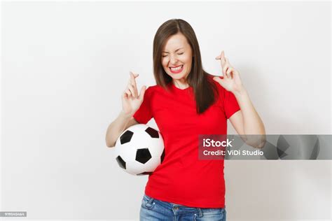 유럽 젊은 여자 축구 팬 이나 선수 빨간색 유니폼 계속 손가락을 엇갈리게 잡고 축구공 흰색 배경에 고립 스포츠 축구 라이프 스타일 개념을 재생 합니다 특별 한 순간을