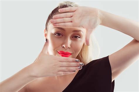 프레임 그녀의 손을 프레이밍하고 흰색 밝은 회색 배경에 고립 된 것처럼 보이는 방법을 좋아 미소 얼굴 미소 사랑스러운 여자의