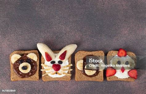 갈색 배경에 딸기 바나나 크림 치즈 초콜릿 코코넛 플레이크가 있는 병아리 곰 토끼 원숭이 모양의 아이들을 위한 4개의 달콤한 토스트 원숭이에 대한 스톡 사진 및 기타 이미지