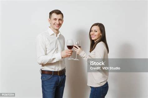 젊은 백인 커플 행복 한 남자와 여자 캐주얼 빛 옷에 사랑에 웃 고 붉은 안경에서 마시는 토스트 만드는 청바지에 고립 된 흰색 배경 와인 광고에 대 한 공간을 복사 합니다