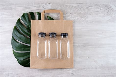 갈색 종이 에코 백에 3 개의 플라스틱 병 로고를 위한 장소 복사 공간이 있는 회색 배경에 친환경 식품 포장 및 면 에코 백 케이터링 및 길거리 패스트푸드용 용기 가방에