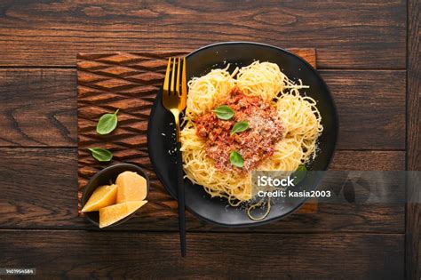 파스타 스파게티 볼로냐세 오래된 나무로 된 소박한 테이블 배경에 흰색 접시에 볼로냐 소스 토마토 소스 치즈 파르 메산 및 바질과 함께 이탈리아 스파게티를 맛있게 식욕을