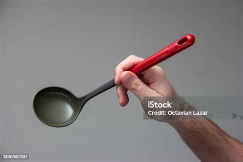 회색 배경에 고립 된 빨간 손잡이와 검은 플라스틱 부엌 국자를 들고 백인 남성 손 검은색에 대한 스톡 사진 및 기타 이미지