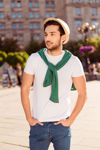 여름 시간입니다 모자와 캐주얼 옷에 강 모와 젊은 잘생긴 남자가 밖에 서 걷고 있습니다 그 세련 된 세련 된 보이는 그의 손은 청바지의 주머니에 남자에 대한 스톡 사진 및