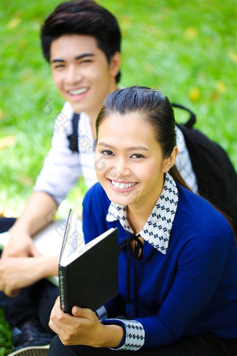 年轻的亚洲学生与书和室外的微笑图片 包图网企业站