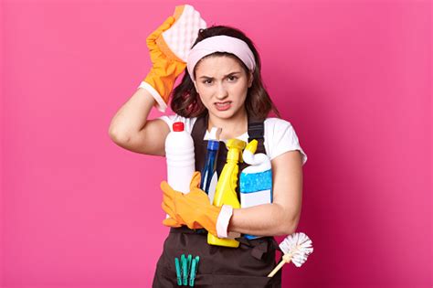 아름 다운 얼굴 표현으로 백인 젊은 여자의 실내 촬영 청소 세제를 보유 머리에 손에 스폰지와 손을 유지 분홍색 스튜디오 배경 위에 고립 집안일을 할 준비가 가사 집안일에