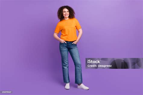 귀여운 사려 깊은 여자가 오렌지 티셔츠를 입고 빈 공간을 찾고 고립 된 보라색 배경의 전체 길이 사진 25 29세에 대한 스톡
