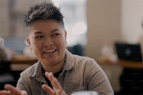 그녀의 얼굴에 미소를 지으며 테이블에 앉아있는 여자 사진 Unsplash의 논바이너리 모델 이미지