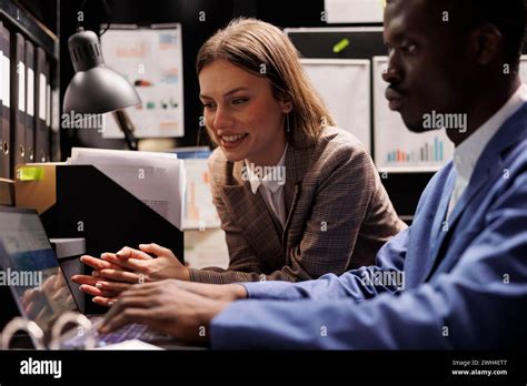 Diverse Police Officers Analyzing Crime Evidence Discussing Criminology Report In Arhive Room