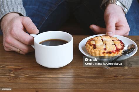 회색 스웨터를 입은 남자는 나무 테이블에 흰색 접시에 고전적인 미국 집에서 만든 체리 파이를 먹는 커피 숍에서 겨울 가을에 검은 Lungo 아메리카노 커피를 마십니다 가을