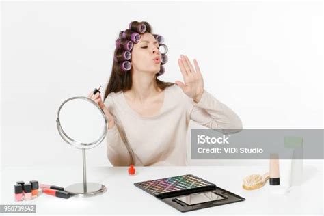 Curlers 빨간색 매니큐어로 손톱 그림 흰색 바탕에 격리 설정된 얼굴 장식 화장품으로 메이크업을 적용 하는 테이블에 앉아