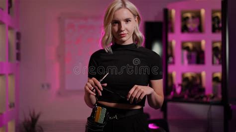 A Girl Barber Poses With Hairdressing Scissors And A Comb In Her Hands