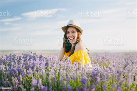 영의 노란 드레스 여름 자연 배경에서 야외에서 보라색 라벤더 꽃 꽃 초원 필드에 모자에에서 아름 다운 여자 흥분 꽃 덤 불 근처 행복 한 여성입니다 라이프 스타일 개념입니다