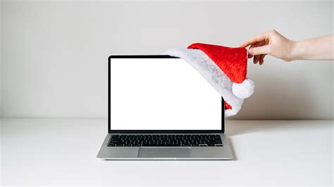 흰색 테이블에 산타클로스 모자가 있는 빈 디스플레이 화면 노트북 컴퓨터 모의 복사 공간이 있는 홈 오피스 책상 작업 공간 크리스마스 온라인 쇼핑 겨울 판매 크리스마스 전자