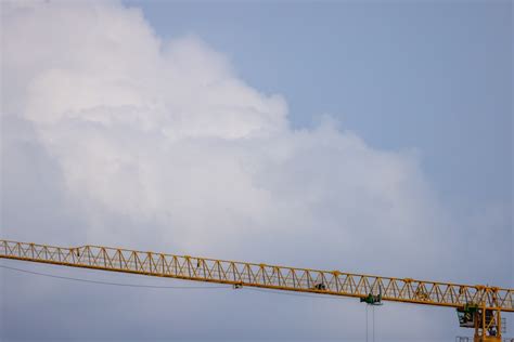 구름 낀 하늘 아래 건물 꼭대기에 앉아 있는 노란 학의 모습 사진 Unsplash의 무료 건축 이미지