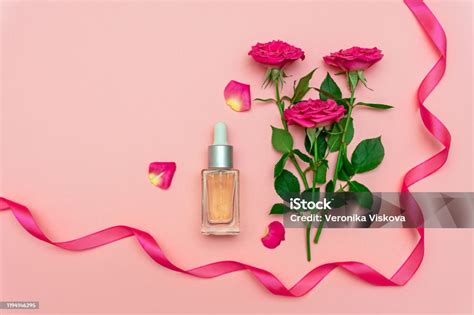 뷰티 컨셉 드롭퍼 유리 병 모형 얼굴 관리를위한 세럼과 분홍색 배경에 리본이있는 핑크 장미 꽃 여성을 위한 선물 복사 공간 플랫