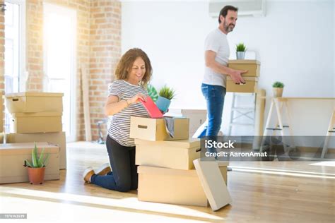 새 집으로 이사하는 중년 노인 부부 새 아파트와 사랑에 행복하게 웃고 있는 여자 골판지 상자 들고 2명에 대한 스톡 사진 및