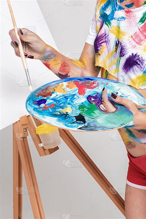 拿着调色板用颜料作画的女艺术家
