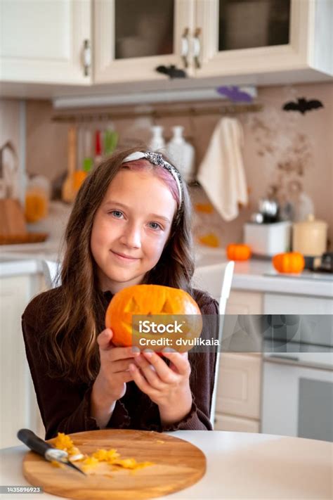 집에서 밝은 흰색 부엌에서 호박에 유령 같은 얼굴을 조각하는 칼을 들고있는 귀여운 10 세 소녀 할로윈 준비 아이에 대한 스톡 사진 및 기타 이미지 Istock