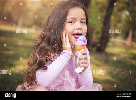 Cute Blonde Curly Haired Girl Eating A Nice Ice Cream In The Forest On