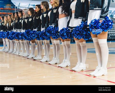 Cheerleaders In Mini Skirts And Knee High Socks Holding Pom Poms Focus