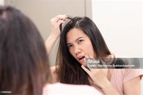 아시아의 아름다운 여성은 거울을 통해 자신을 바라보고 머리카락을 당기고 탈모와 회색 머리카락에 대한 걱정으로 입술을 만집니다 갈색에 대한 스톡 사진 및 기타 이미지 Istock