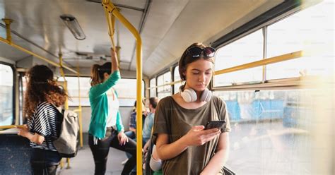 갈색 머리와 헤드폰을 목에 두른 아름다운 백인 소녀가 대중 교통에 서 있는 동안 스마트폰을 사용하여 메시지를 읽거나 보냅니다 사진 Unsplash의 여행하다 이미지