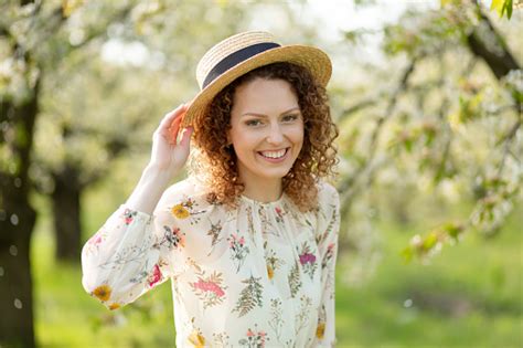 세련된 고리 버들 모자에 곱슬 머리를 가진 초상화 젊은 매력적인 여자는 봄 날에 피는 녹색 정원을 즐긴다 감정에 대한 스톡 사진 및 기타 이미지 Istock