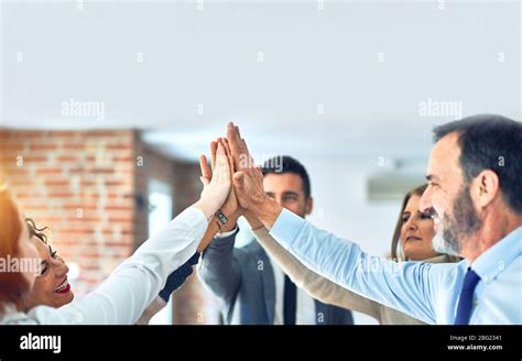 Group Of Business Workers Standing With Hands Together Highing Five At