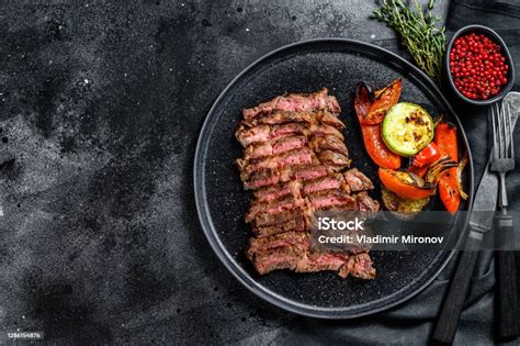 얇게 썬 구운 쇠고기 대리석 희귀 스테이크 야채 반찬을 곁들인 접시에 척 아이 롤 검은 색 배경 맨 위 보기입니다 복사 공간 Celebrity Roast에 대한 스톡 사진