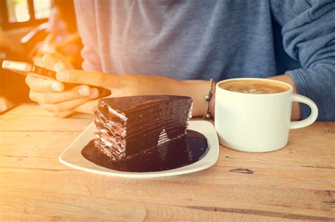 여자는 커피 컵과 초콜릿 케이크와 휴대 전화를 사용합니다 갈색에 대한 스톡 사진 및 기타 이미지 갈색 검은색 고풍스런