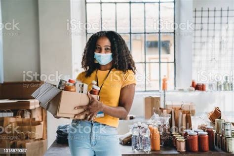 푸드 뱅크에서 음식과 음료의 골판지 상자를 들고 혼합 인종 자원 봉사 여성의 초상화 자선 및 구제 사업에 대한 스톡 사진 및