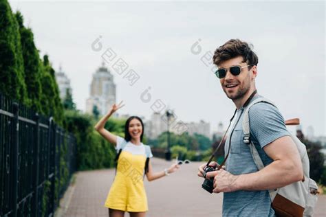 英俊的男人与数码相机和亚洲女人看着相机图片 包图网企业站