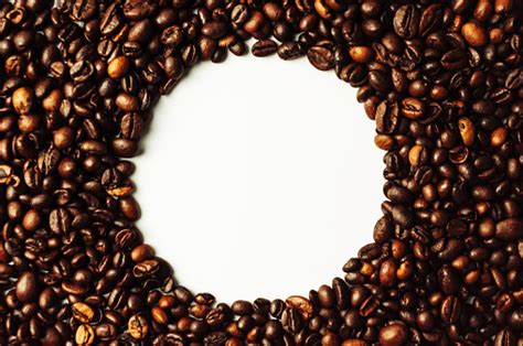커피 콩은 빈 흰색 배경에 표면에 흩어져 있습니다 갈색 커피 콩 한 줌 비문 텍스트 또는 원형 로고를 위한 복사 공간이 있는