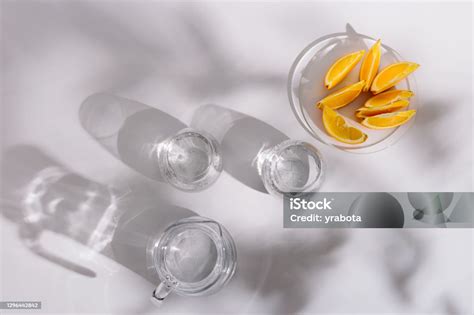 화창한 날에 흰색 배경에 접시에 레몬 조각과 아름다운 유리 잔에 천연 물을 마시는 여름 최소한의 평평한 누워 하드 그림자 물에 대한 스톡 사진 및 기타 이미지 Istock