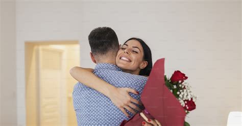 발렌타인 데이 개념입니다 사랑에 빠진 행복한 커플 발렌타인 데이를 축하하는 젊은 사랑하는 커플 서로 껴안는 연인들 잘 생긴 남자는 집에서 빨간 장미로 여자 친구를