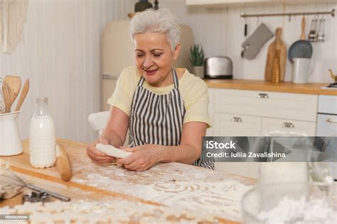 부엌에서 요리하는 행복한 노인 여자 세련 된 오래 된 성인 회색 머리 숙녀 할머니 반죽 반죽 굽기 쿠키 늙은 할머니는 집에서 만든 음식을 요리합니다 가정 주부 가사 개념
