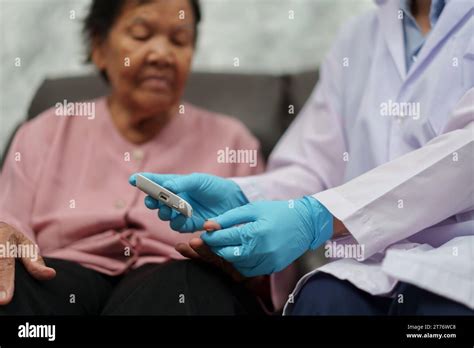 Close Up Doctor Using Glucometer Checking Blood Sugar Level Of Senior