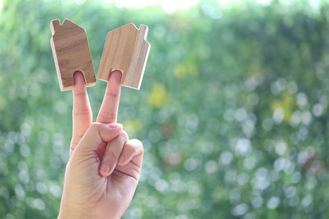 모델 하우스와 여성의 부드러운 초점 은 자연 녹색 배경에 기호 두 손가락 이나 승리 제스처를 만드는 새로운 가정 및 부동산 개념