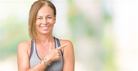 격리 된 배경에 손과 얼굴에 행복 하 고 자연 식 가진 측까지 손가락으로 가리키는 얼굴의 미소와 쾌활 한 스포츠 옷을 입고 아름 다운 중 년 여자 가리키기에 대한 스톡 사진