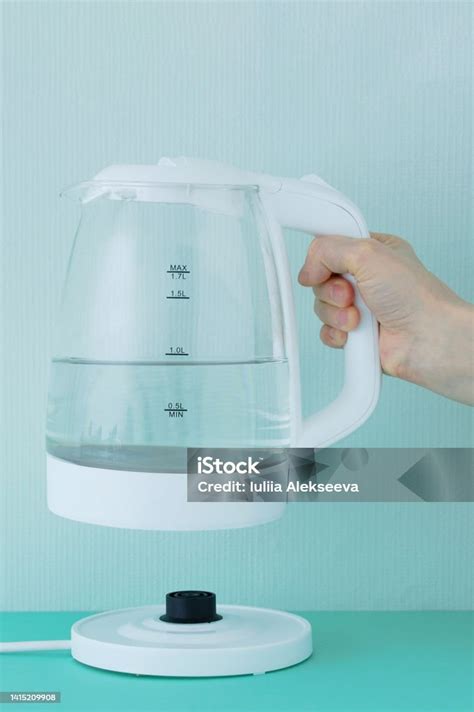 손에 물이 든 흰색 유리 주전자 주전자를 전기 플랫폼에 놓습니다 끓음에 대한 스톡 사진 및 기타 이미지 끓음 물 전기 주전자 Istock